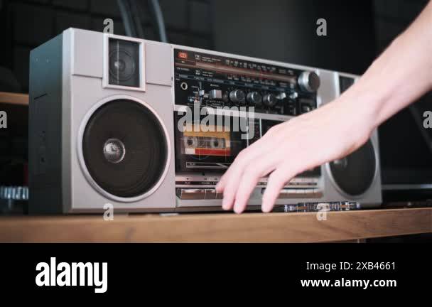 A hand ejects a cassette tape from a vintage boombox, demonstrating the ...
