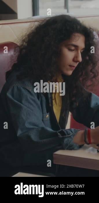 Vertical side shot of gen Z Caucasian man with curly hair choosing meal ...
