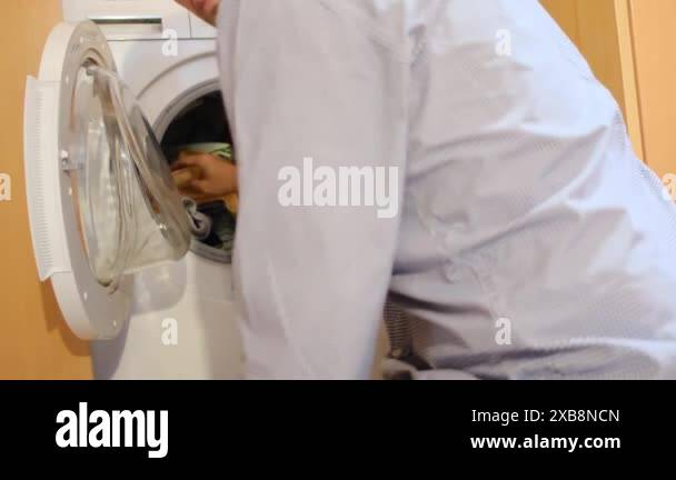 Man washing children's clothes in washing machine. Break with the ...