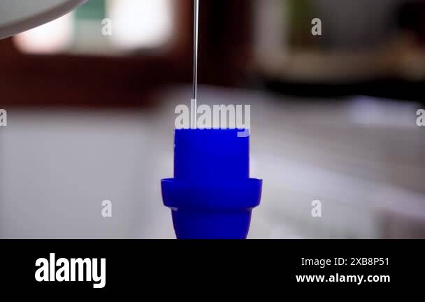 Pouring liquid blue detergent into a measuring cap for a washing ...