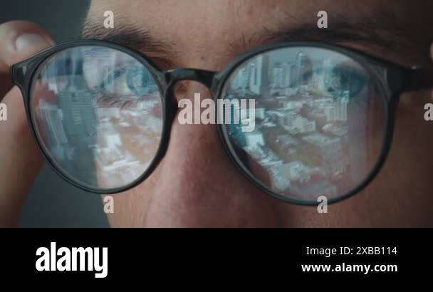 Man in glasses gazes through lenses reflecting architecture of city ...