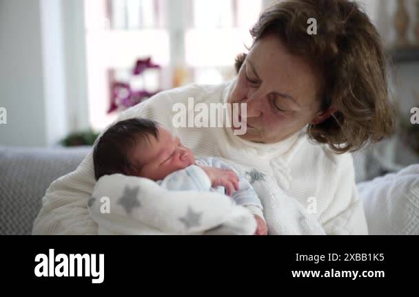 Elderly woman gazing lovingly at newborn baby, heartfelt family moment ...