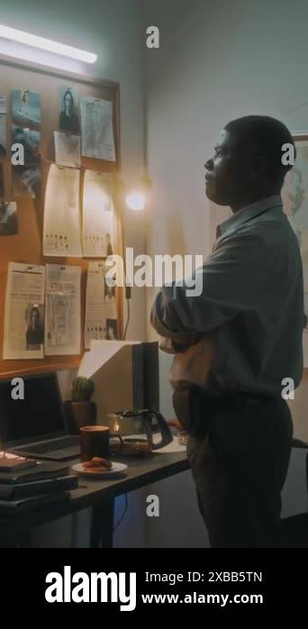 Medium vertical shot of African American police detective standing in ...