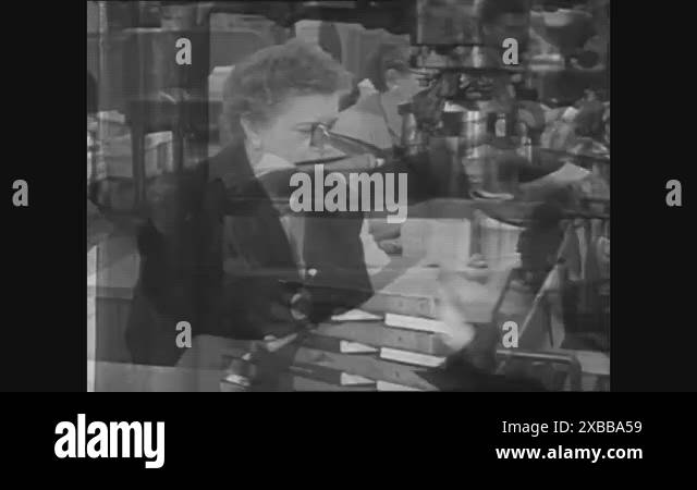 Female workers assemble pages and insert into a saddle for binding at a ...