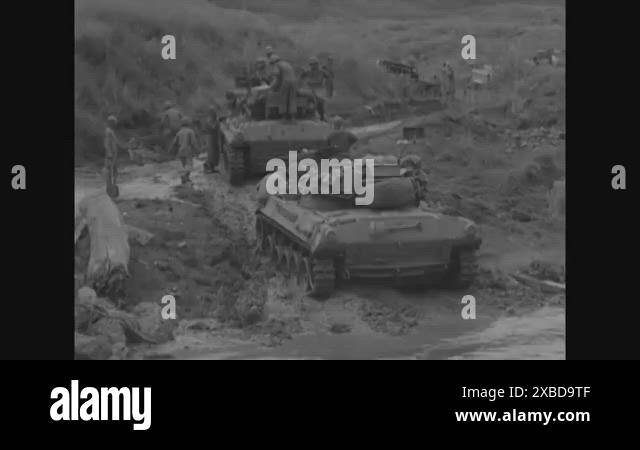 PHILIPPINES - 1945 - WWII allied forces cross stream with Two M18 Hellcat tanks and one M7 tank ...