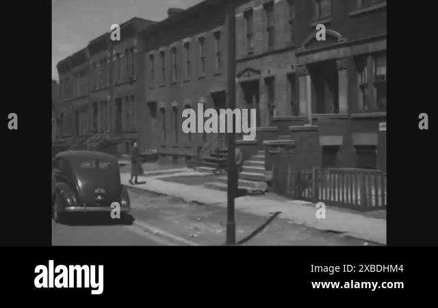 1930s - Cars and buses drive through the slums of a poor neighborhood ...