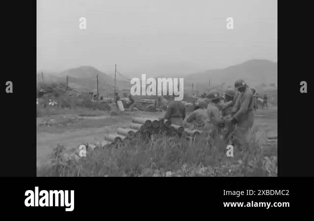 CHORWON - 1951 - Black 58th Field Artillery soldiers load and fire a 105mm howitzer under a ...