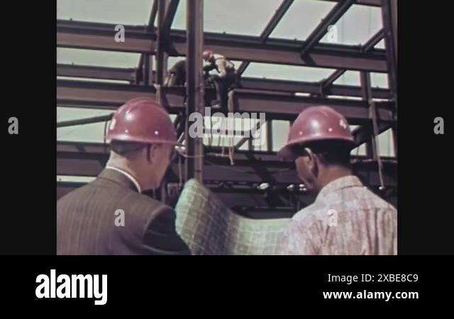1960 - Construction workers look over blueprints on a site and steel ...
