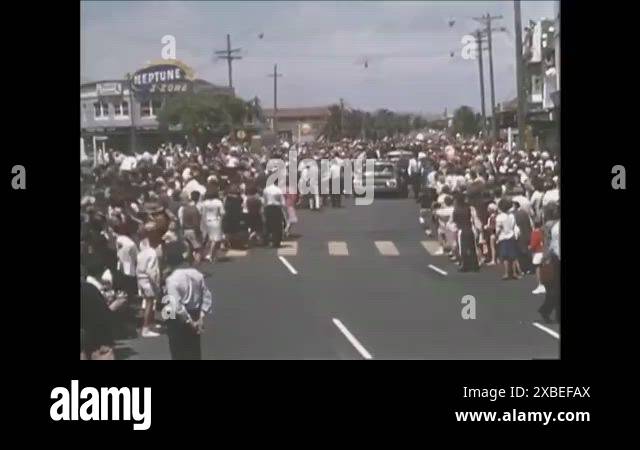 A presidential motorcade and crowds and balloons and confetti are shown ...