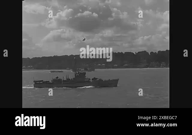 A seaman attaches a flag to a line and tugs are shown in transit in the ...