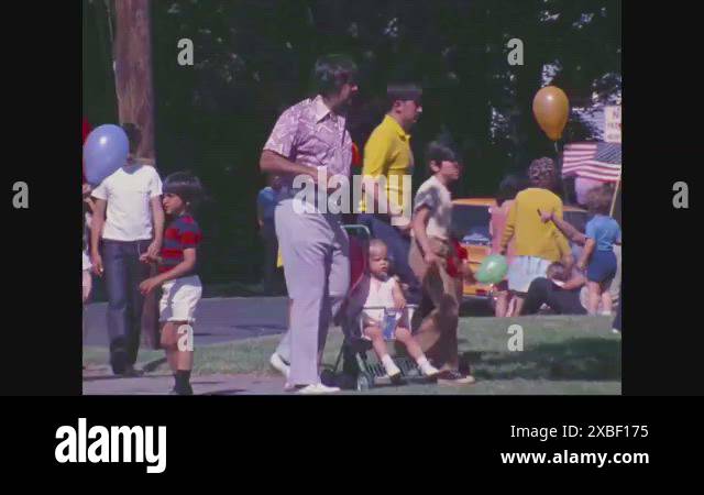 1970s - Families line a parade route, holding balloons, as a patriotic ...