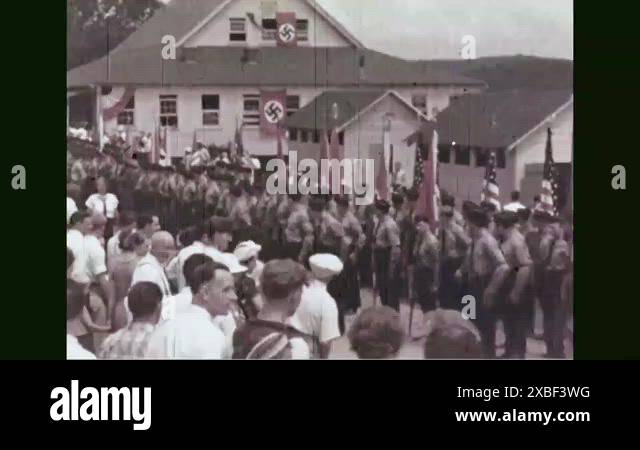 Civilians and soldiers and a military band gather and salute and Nazi ...