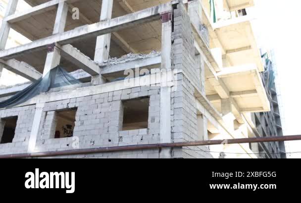 Building under construction stands with skeletal framework. Sun casts ...