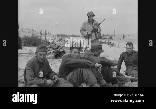 1944 - Men of the US Navy guard German POWs on the beach. They ...