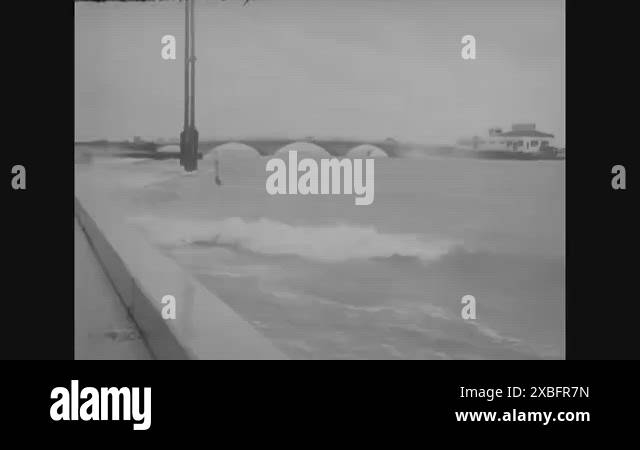 Waves wash over a bridge and a pier and stormy seas are shown during a ...