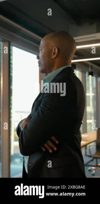 Aframerican entrepreneur standing near huge modern office window with ...