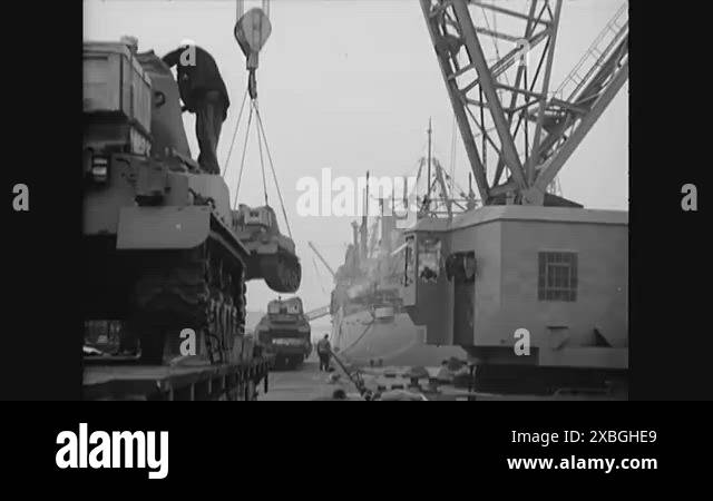 A crane is used to lift a tank and a cargo ship is shown at a military ...