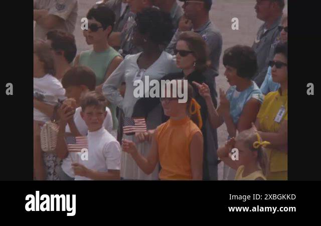 A crowd of people wait at an airport to meet the Apollo 11 astronauts ...