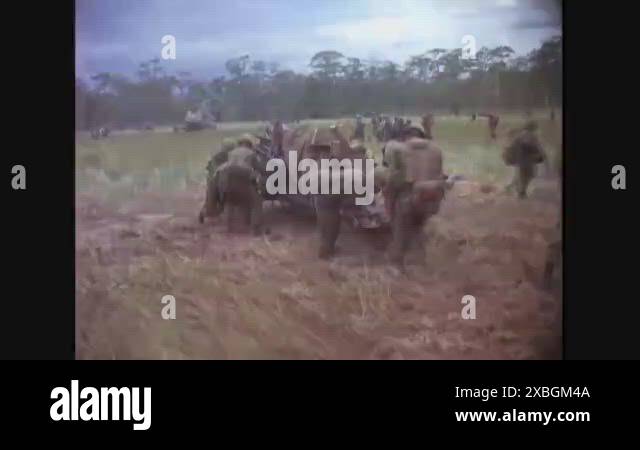 1965 - Soldiers load a 105mm howitzer into a CH-47 helicopter, a ...
