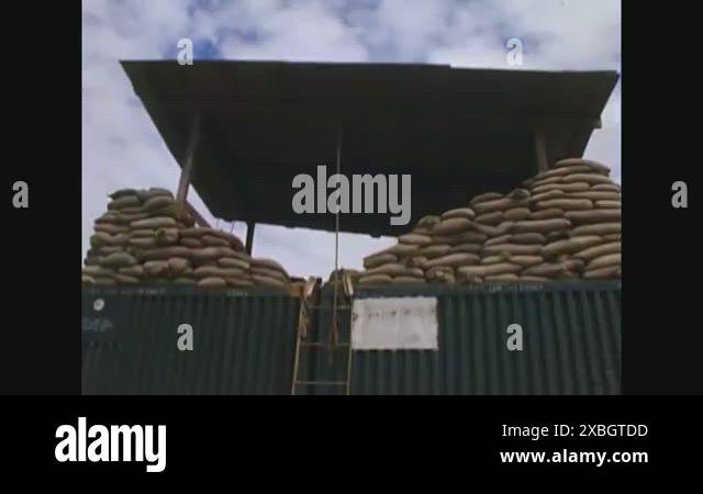 1967 - A helicopter landing area and building materials are seen by a ...