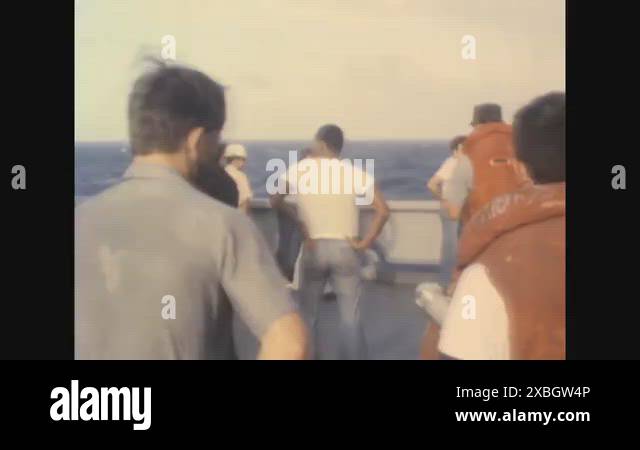 A machine gun is fired and Vietnamese refugees are brought to a warship ...