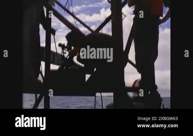 Crewmen use a theodolite and radioing is shown during an array barge ...