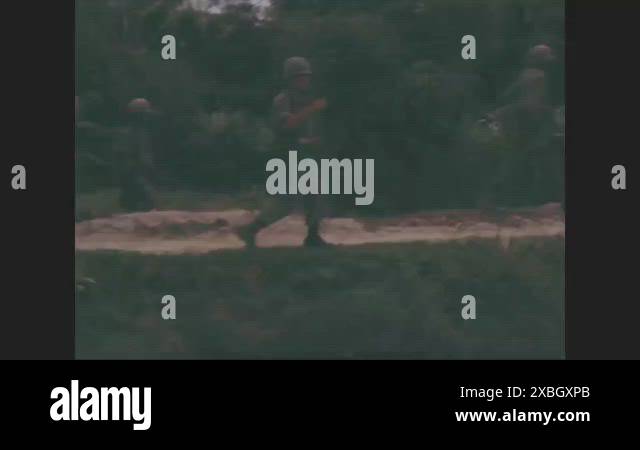 American soldiers walk through the jungles of Vietnam and light a hut ...