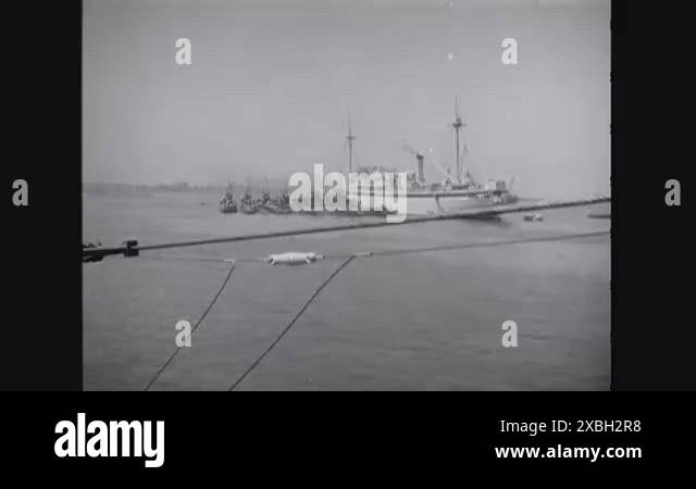 1948 - A fleet of old-fashioned submarines is seen sailing by a warship ...