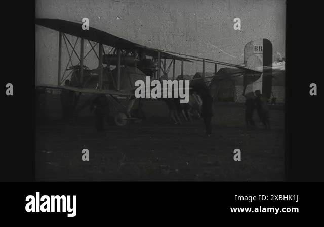 A French biplane is positioned on an airfield and a gunner fires a ...