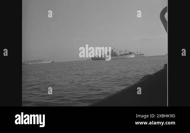 Cargo is lifted in a net and warships are shown at Hungnam Harbor ...