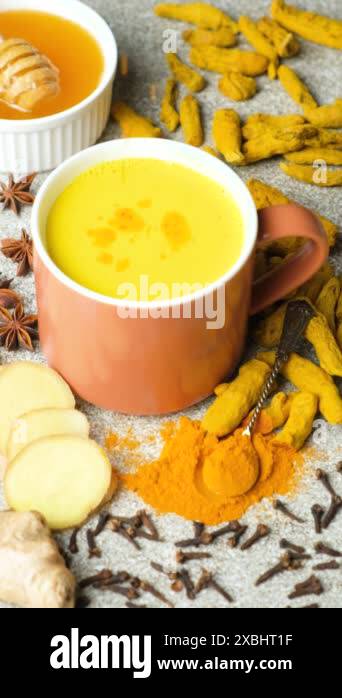Ground turmeric pouring into golden milk, making a traditional ...