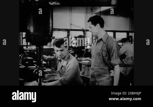 1944 - The set-up man at a factory helps a new hire with his drill ...