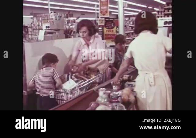 1960s - A cashier helps a woman check out at the grocery store while ...
