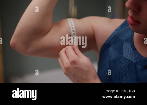 A close-up shot capturing a man carefully measuring his biceps inside a ...
