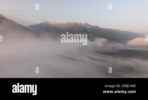 A breathtaking drone flight captures the majestic beauty of towering mountains piercing through ...