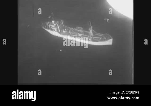 1940s - Aerial footage shows rescue vessels approaching a sinking ship ...