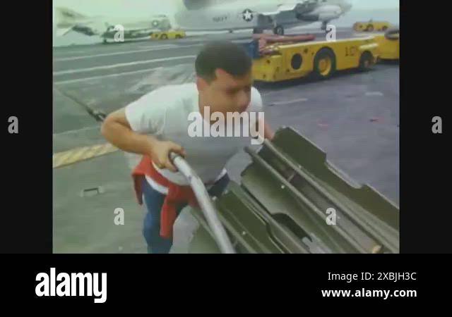 1967 - US Navy seamen wheel carts of bombs on the flight deck of the ...