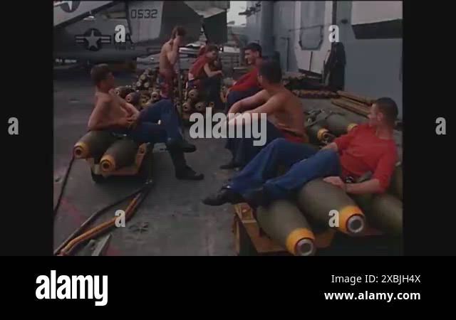 1967 - US Navy seamen wheel carts of bombs on the flight deck of the ...