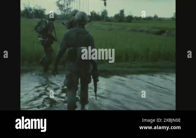1968 - American soldiers cross a stream in Vietnam and check the ...