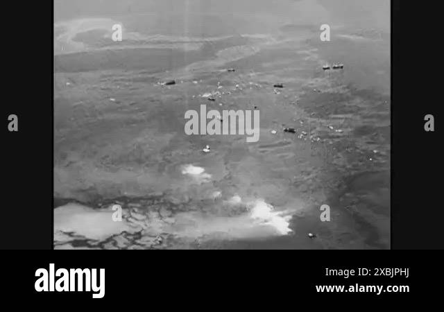 A warship burns and firefighting is shown and a wounded soldier is ...