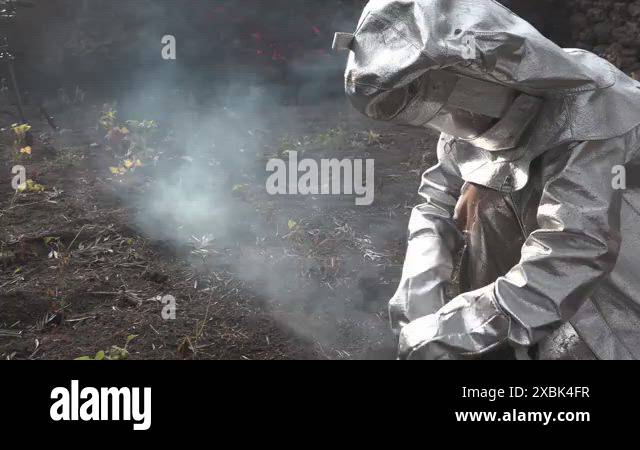 A man in a fireproof suit examines lava flows from the Cabo Verde ...