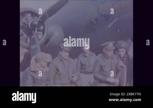 1943 - Airmen pose and a warplane is pulled onto an airstrip and a tail ...
