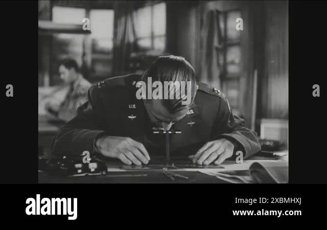 1943 - A US Army Air Force sergeant lines up reconnaissance photos on a ...