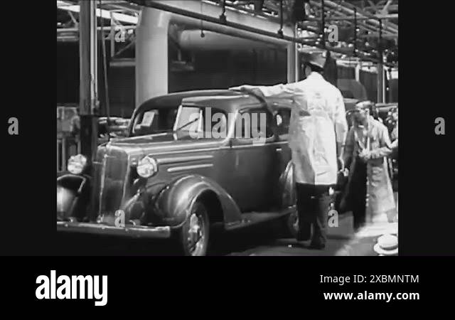 1936 - A tall automobile worker inspects a car on an assembly line at a ...