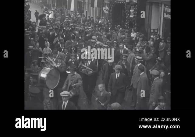 1922 - A group of people parade down a street, a band plays in a parade ...