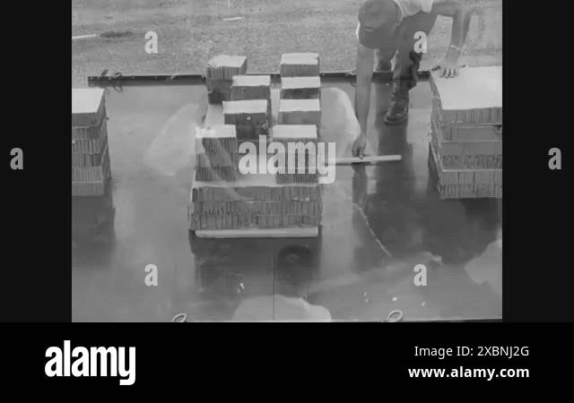 Parachute riggers load a jeep onto honeycomb padding and attach and ...