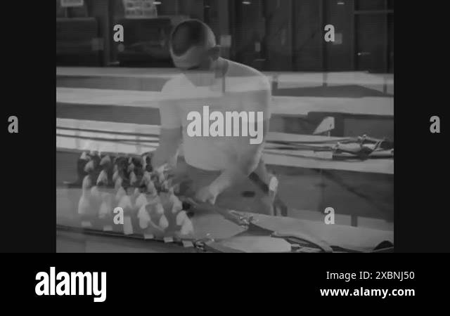 An inspector watches as parachute riggers practice packing a G11 A ...