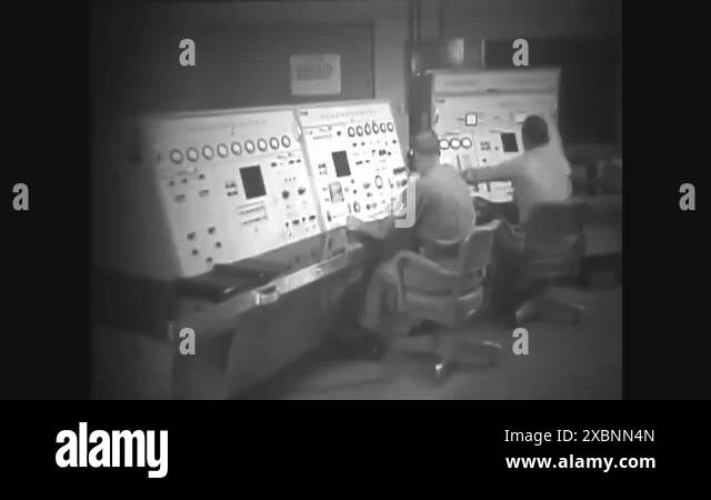 1961 - Flight controllers at workstations press buttons and turn knobs ...