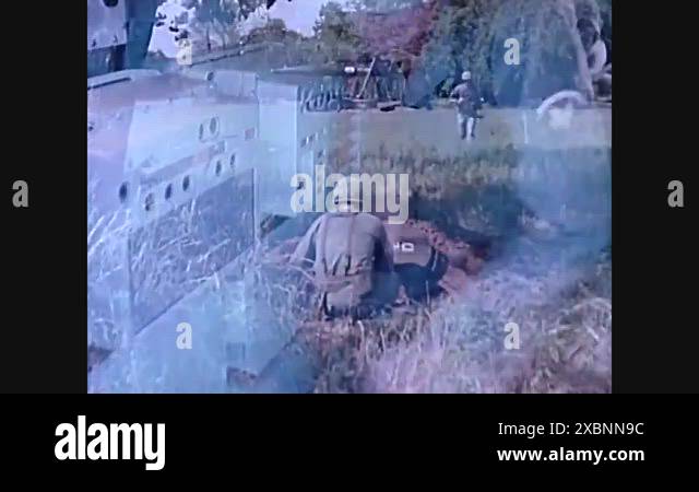 1965 - Soldiers in a remote firing position in a field wait through an ...
