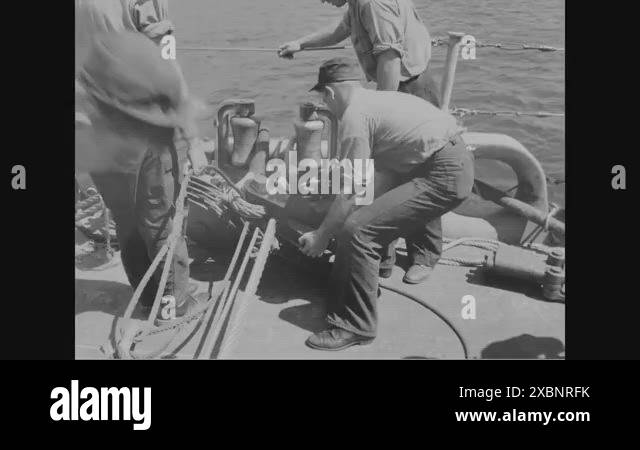 1959 - Crewmen lower a cable and a SCUBA diver swims alongside as ...